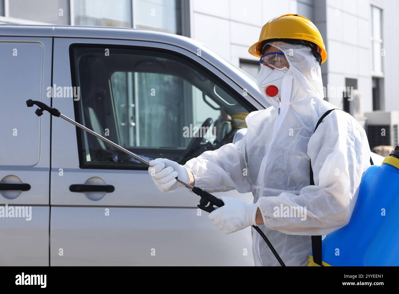 Pest control worker with spray tank near gray minibus outdoors Stock ...