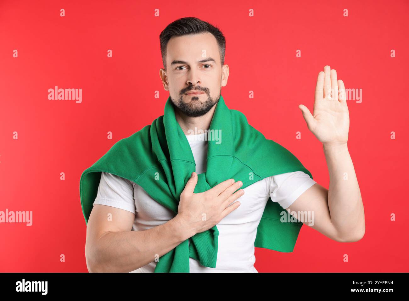 Man making promise with raised hand on red background. Oath gesture ...