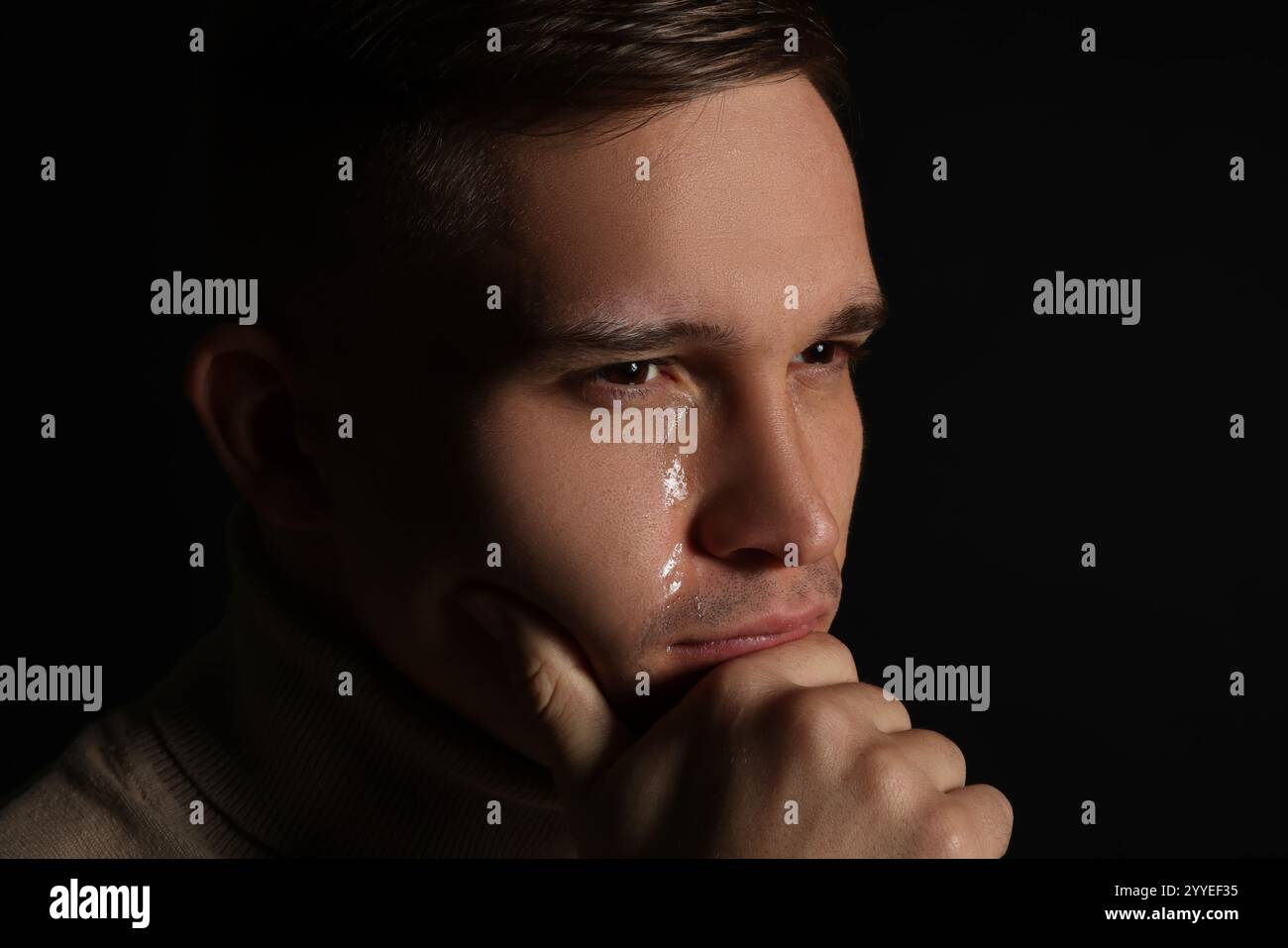 Distressed young man crying on black background, closeup Stock Photo ...