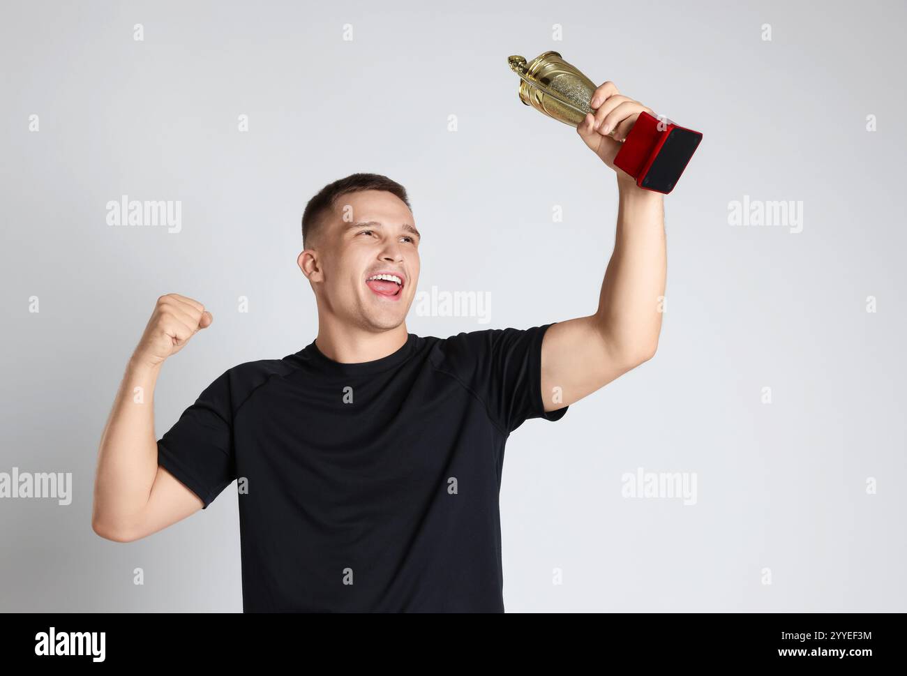 Happy winner with golden trophy cup on light grey background Stock ...