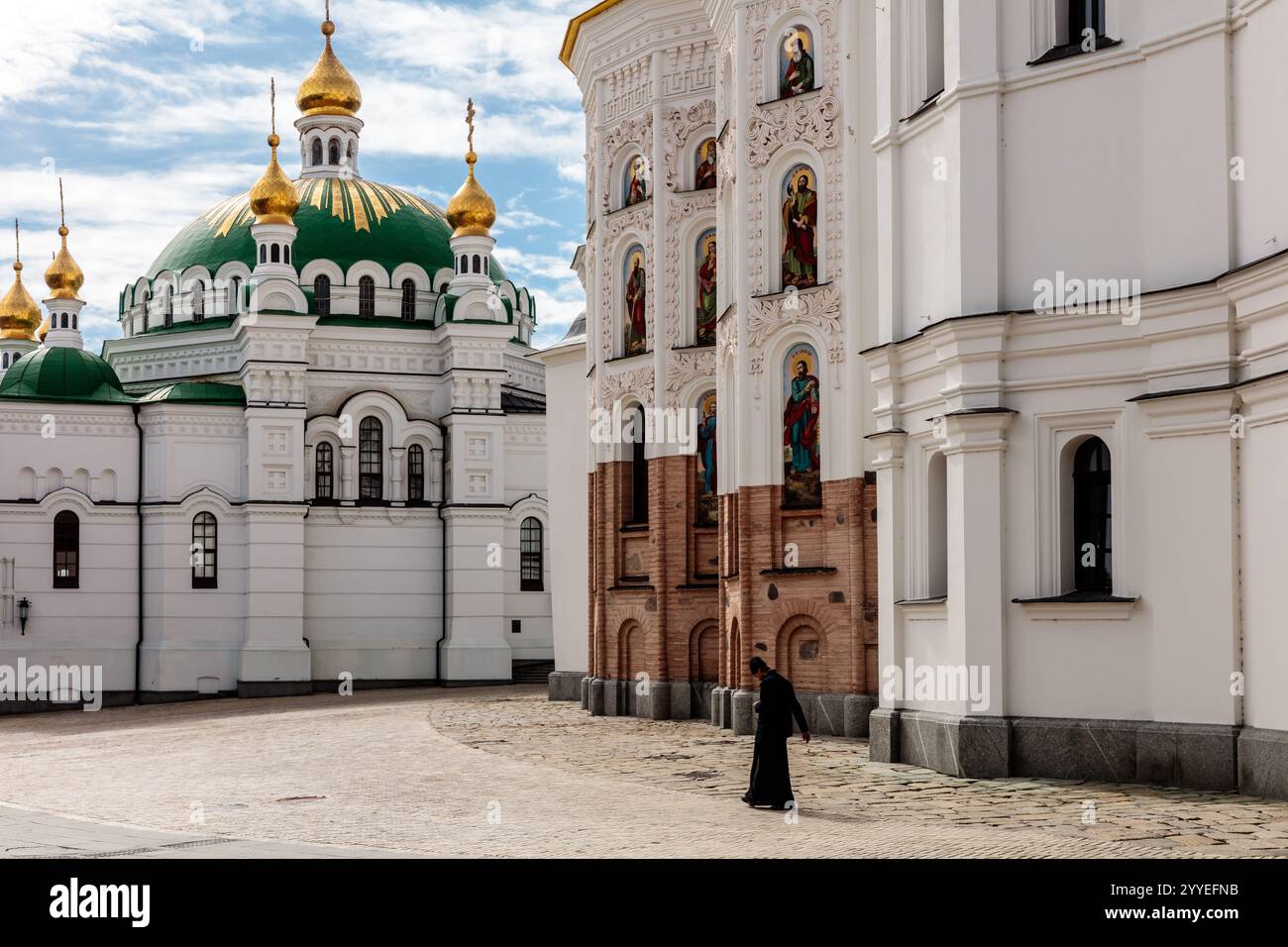 A woman walks past a church with a green dome. The church is surrounded ...