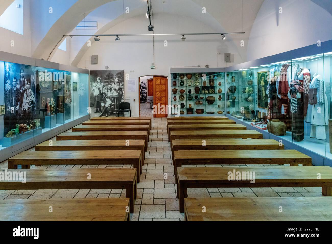 A museum with a lot of tables and chairs. The tables are empty. The ...