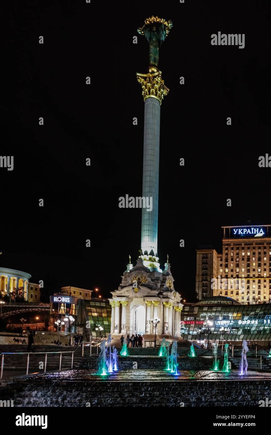 A tall white and gold column with a green fountain in front of it. The ...
