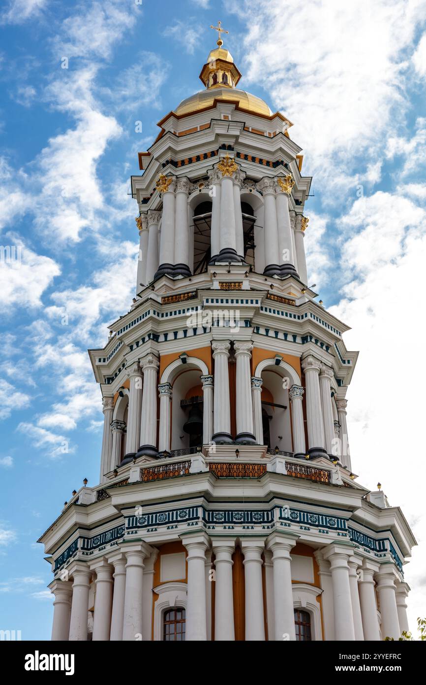A tall, white and gold tower with a gold dome. The tower is surrounded ...