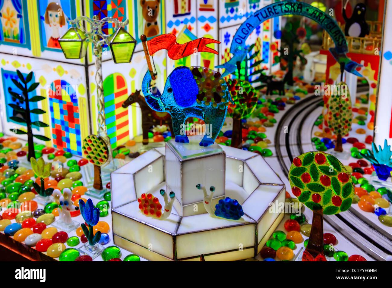 A colorful scene of a town with a large elephant statue in the center ...