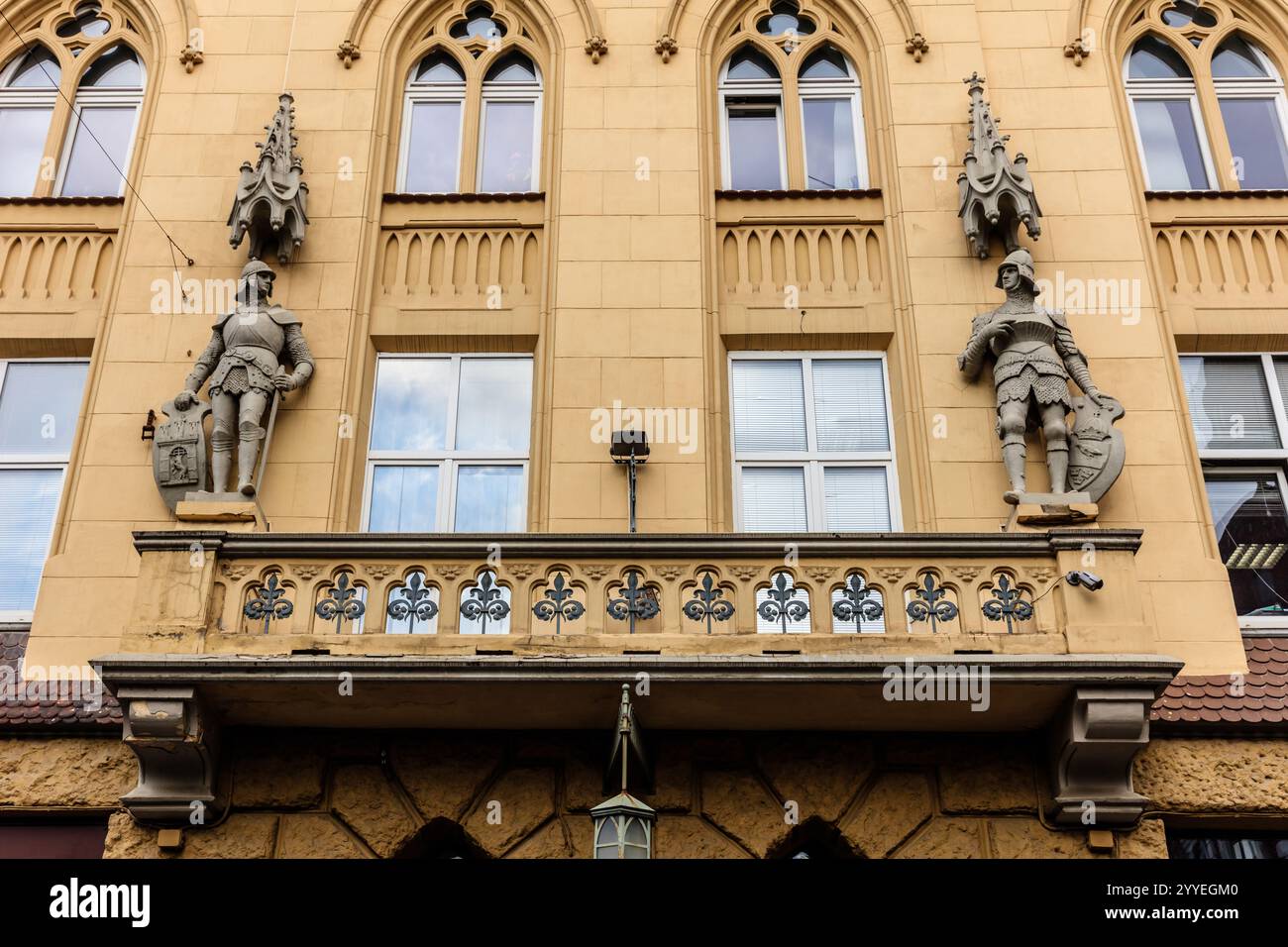The building has statues of men on the balcony. The building is old and ...
