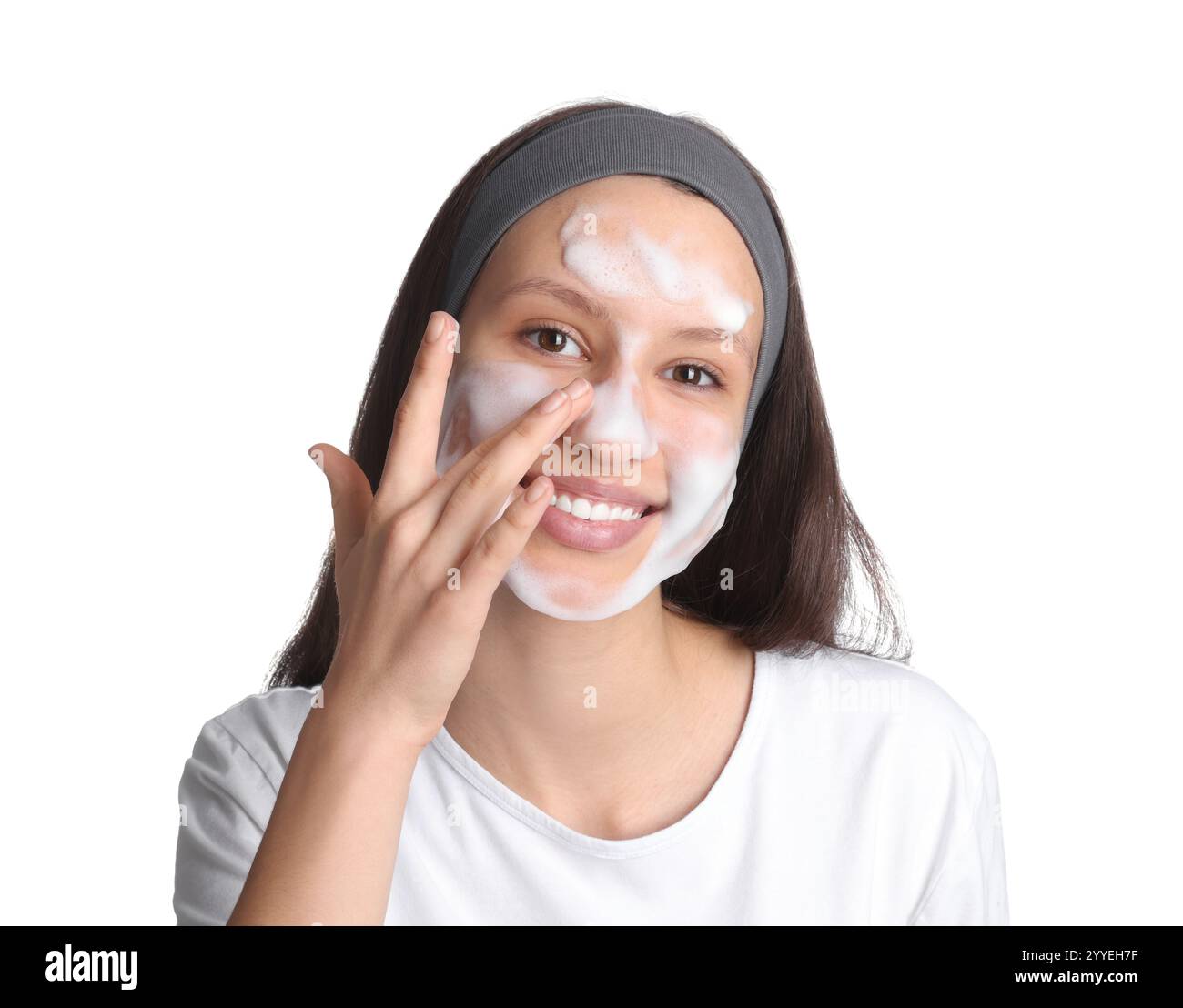 Teenage girl washing her face with cleanser on white background ...