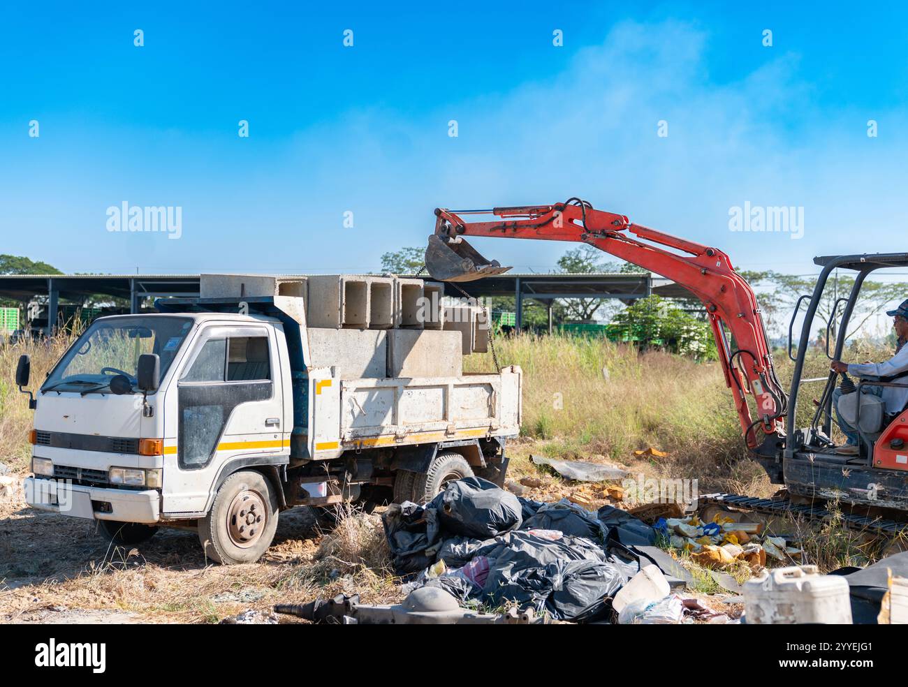 Small excavator lift drain water load to truck in plant Stock Photo - Alamy