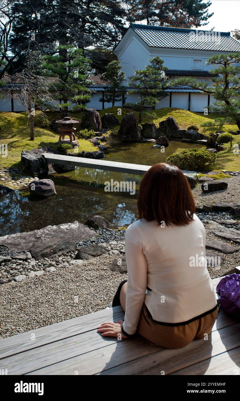 Woman sitting on a veranda contemplating the beauty of a Japanese Zen ...