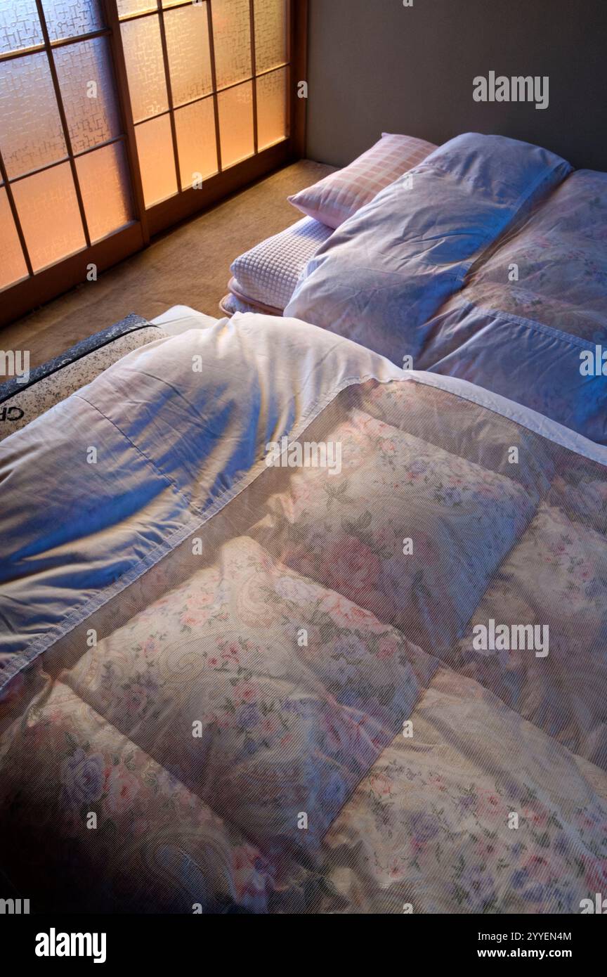 Japanese futon bedding on the floor in a residential bedroom with ...