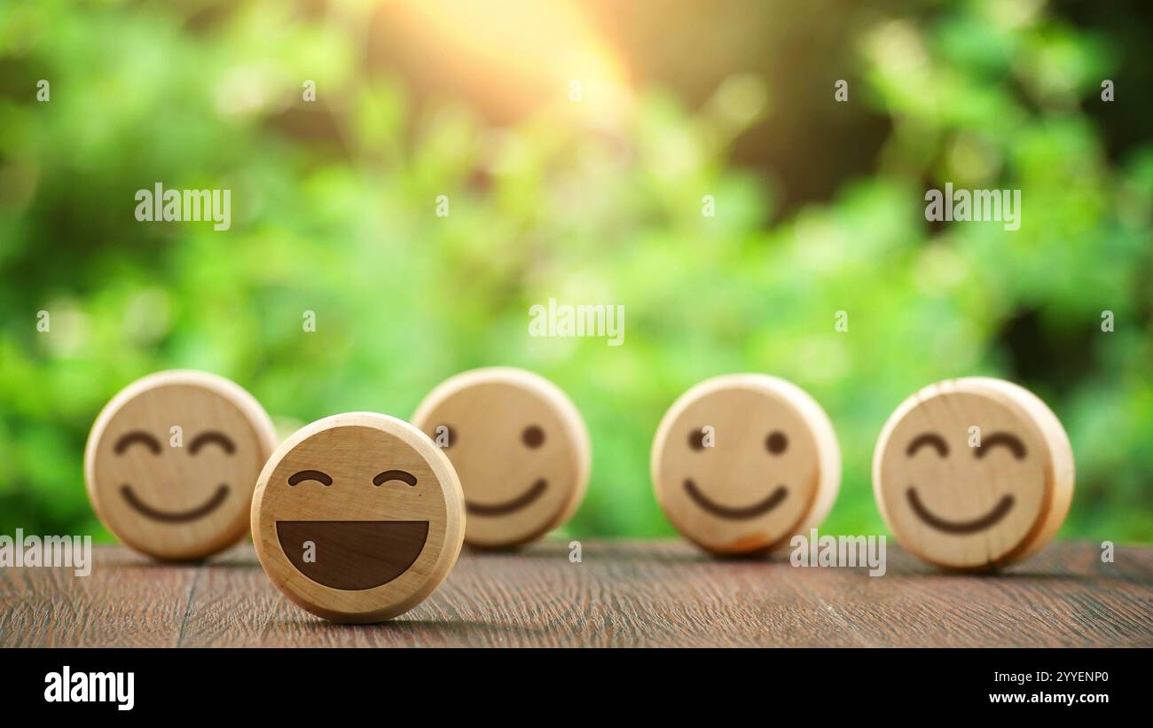 Five smiling faces carved on a round wooden surface with a background ...