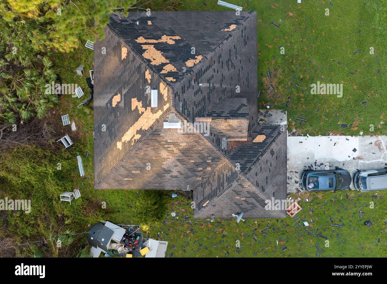 Wind damaged house roof with missing asphalt shingles after hurricane ...
