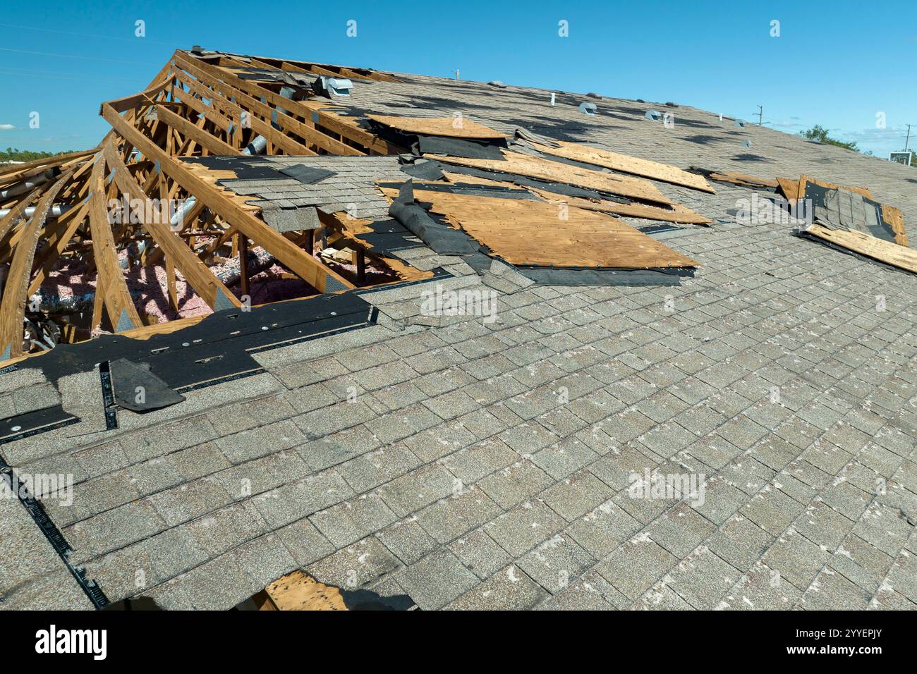 Wind damaged house roof with missing asphalt shingles after hurricane ...