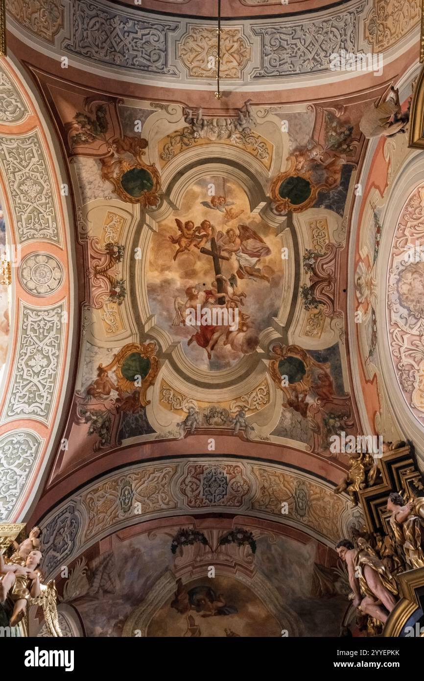 The ceiling of a church is decorated with a painting of a cross and ...