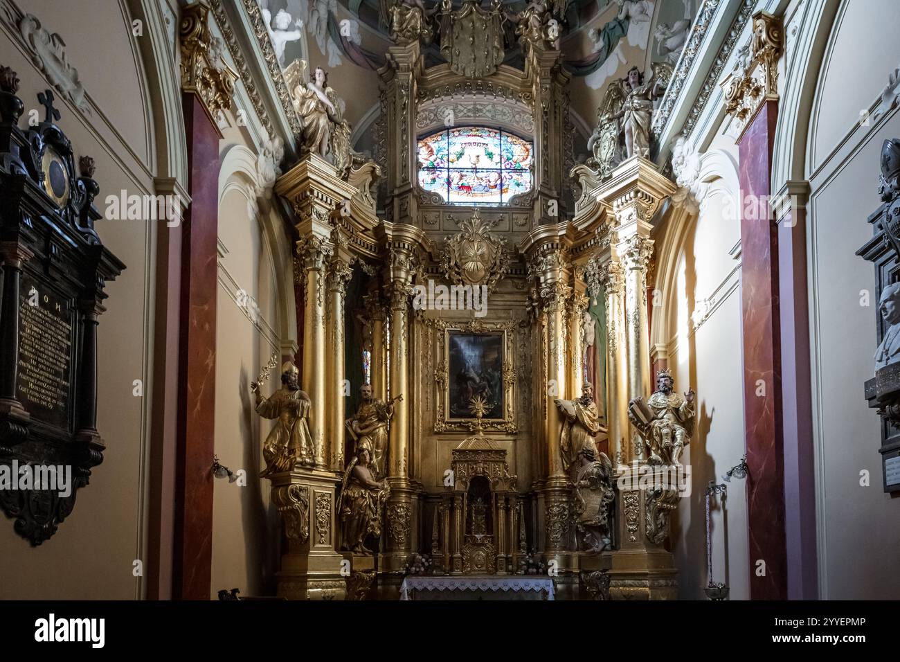 The interior of a church is decorated with gold and stained glass ...