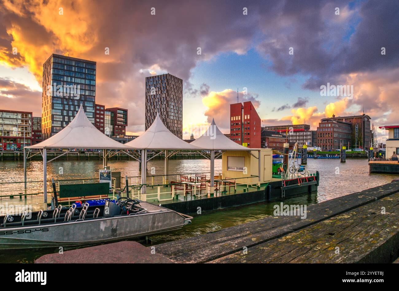 Cityscape at sunset with boat restaurant in front and high rises ...