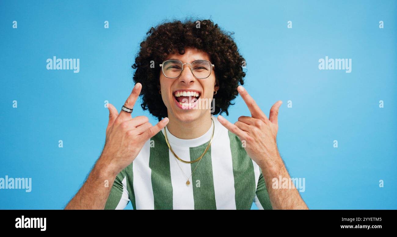 Portrait, rock on and hand gesture with man in studio on blue ...