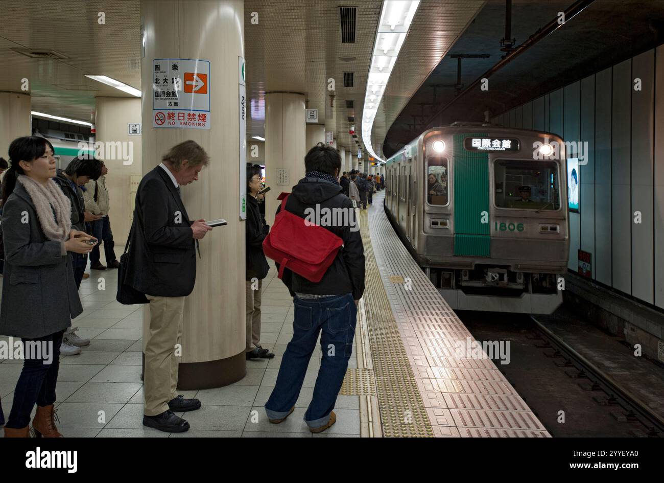 Passengers patiently waiting on the platform in a queue for the ...