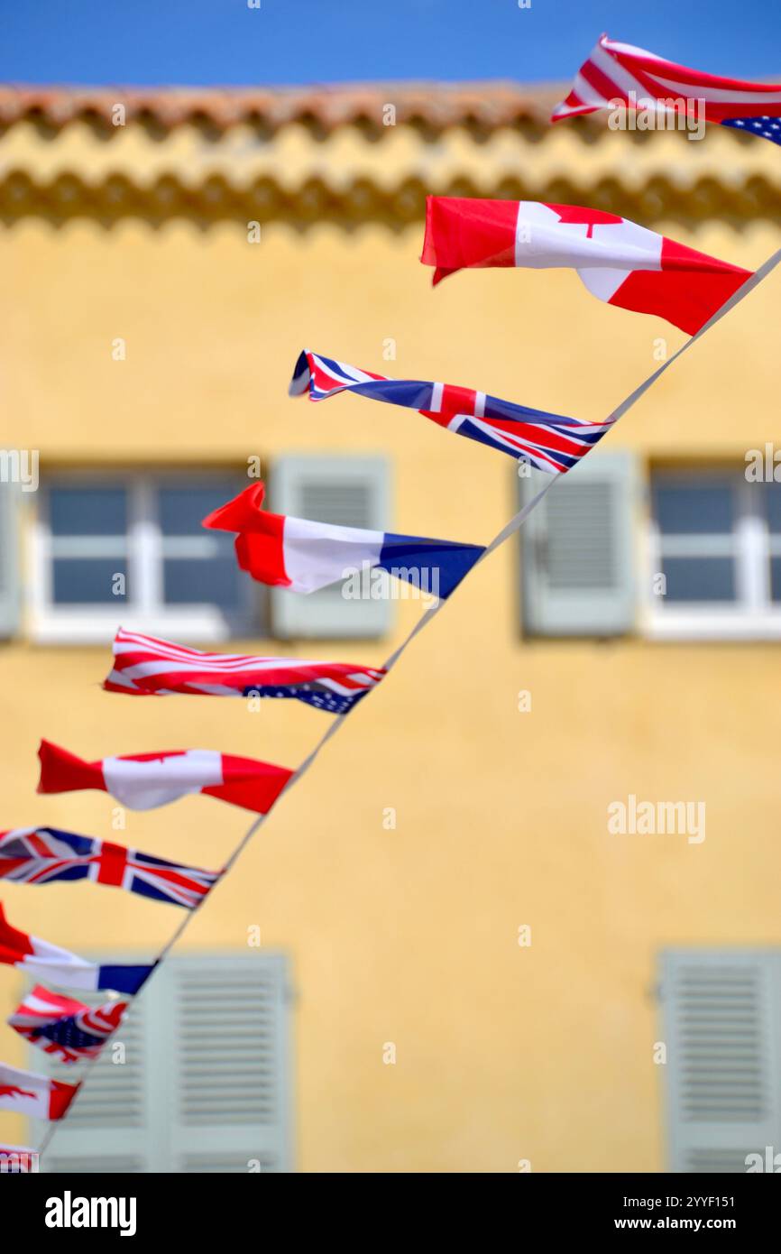 Flags fluttering in the breeze outside a classic ochre coloured house ...