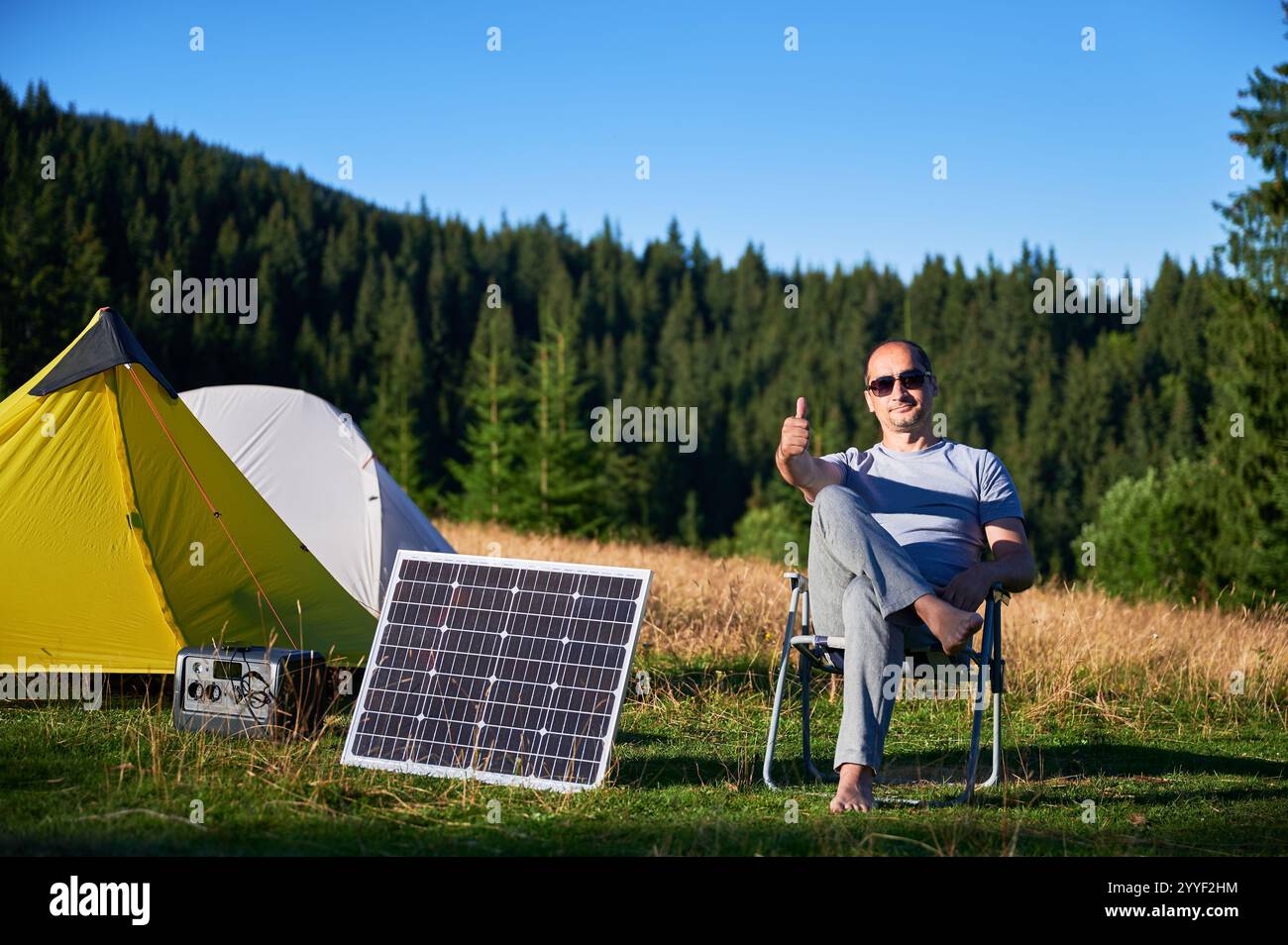 Man using photovoltaic solar panel for charging portable power station ...
