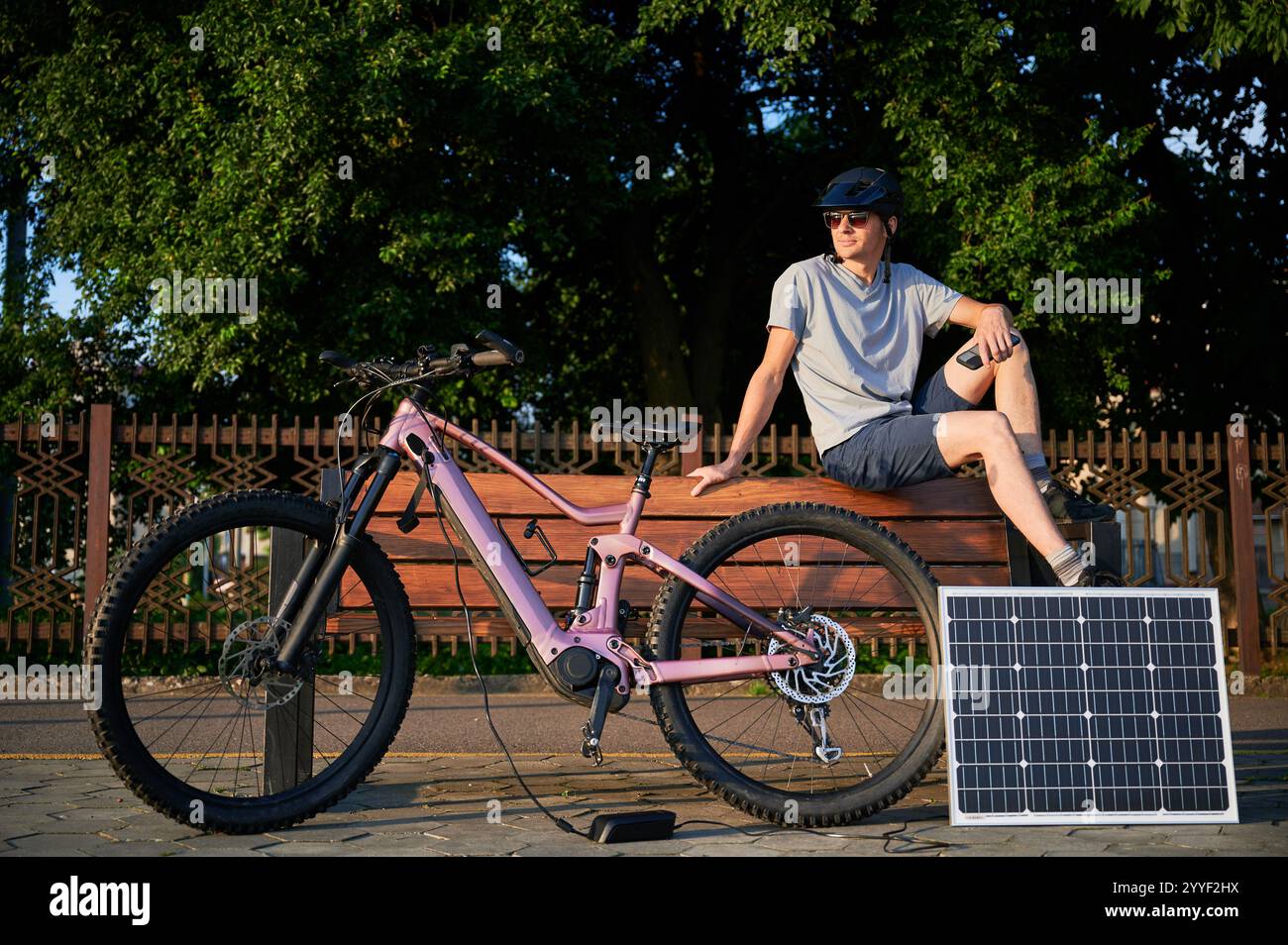 Man cyclist using solar panel for charging electric mountain bike ...