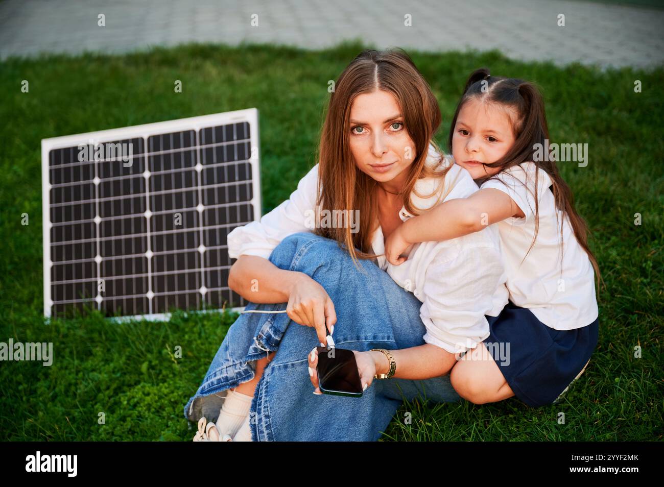 Mother connecting smartphone to photovoltaic solar panel for charging ...