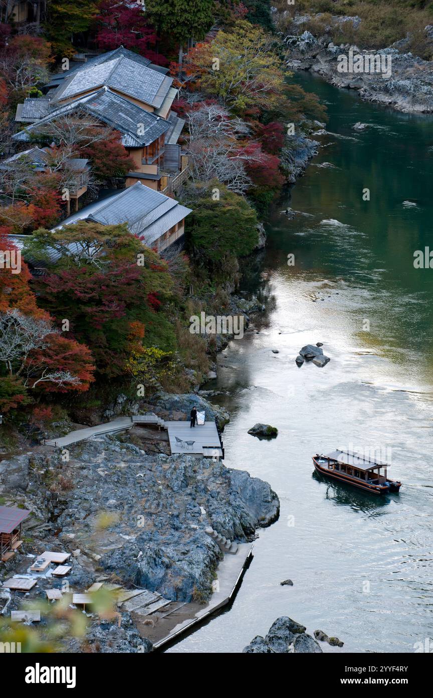 A sightseeing boat on the Hozugawa River passing by the riverside ...