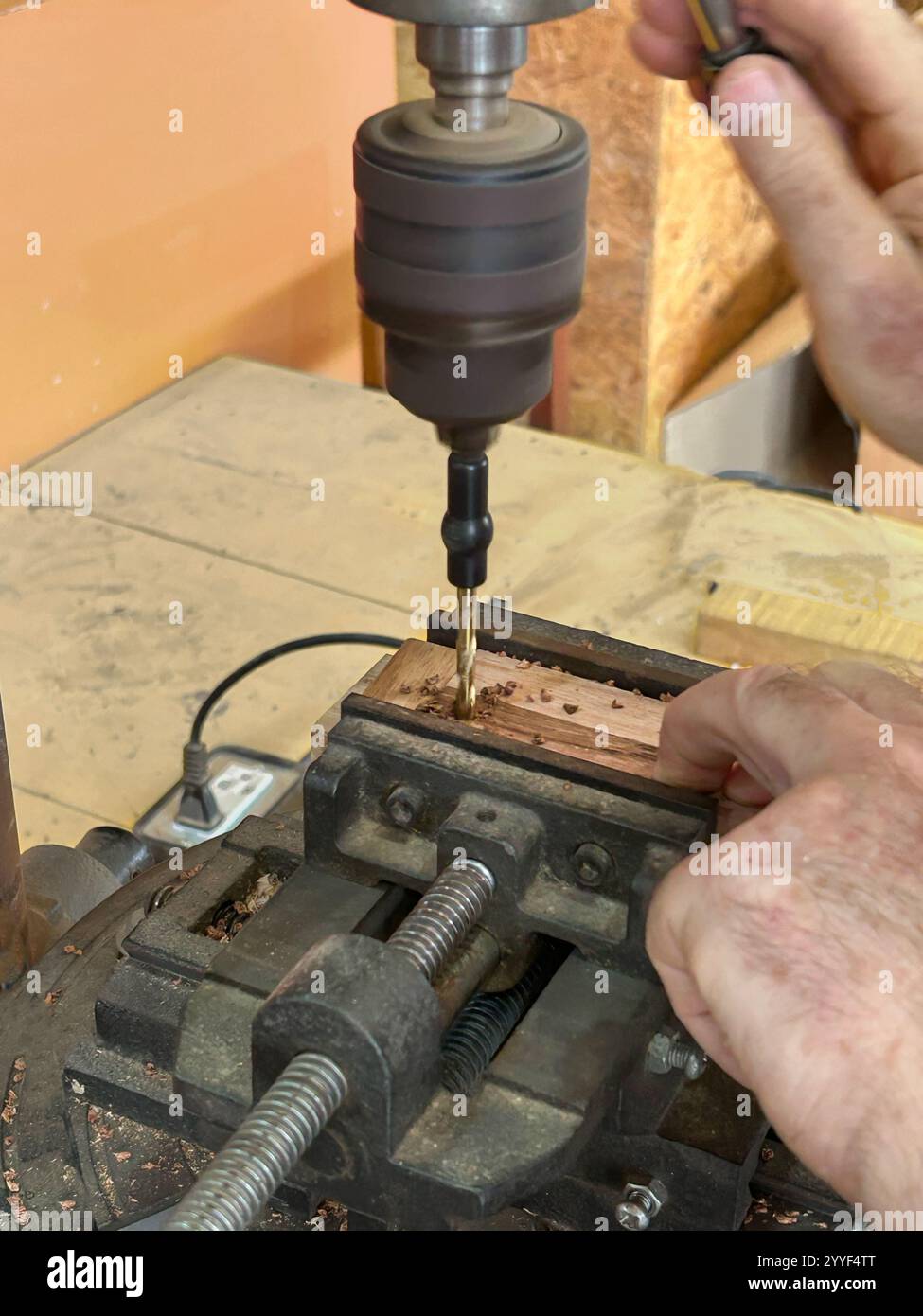 Wood worker man using drill press machine for make a hole on wood parts ...