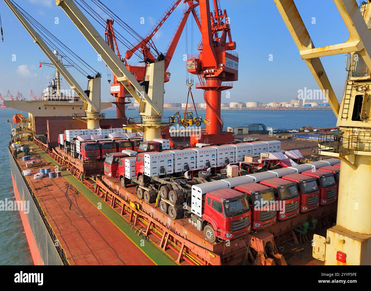 YANTAI, CHINA- DECEMBER 22, 2024 - A crane loads construction vehicles ...