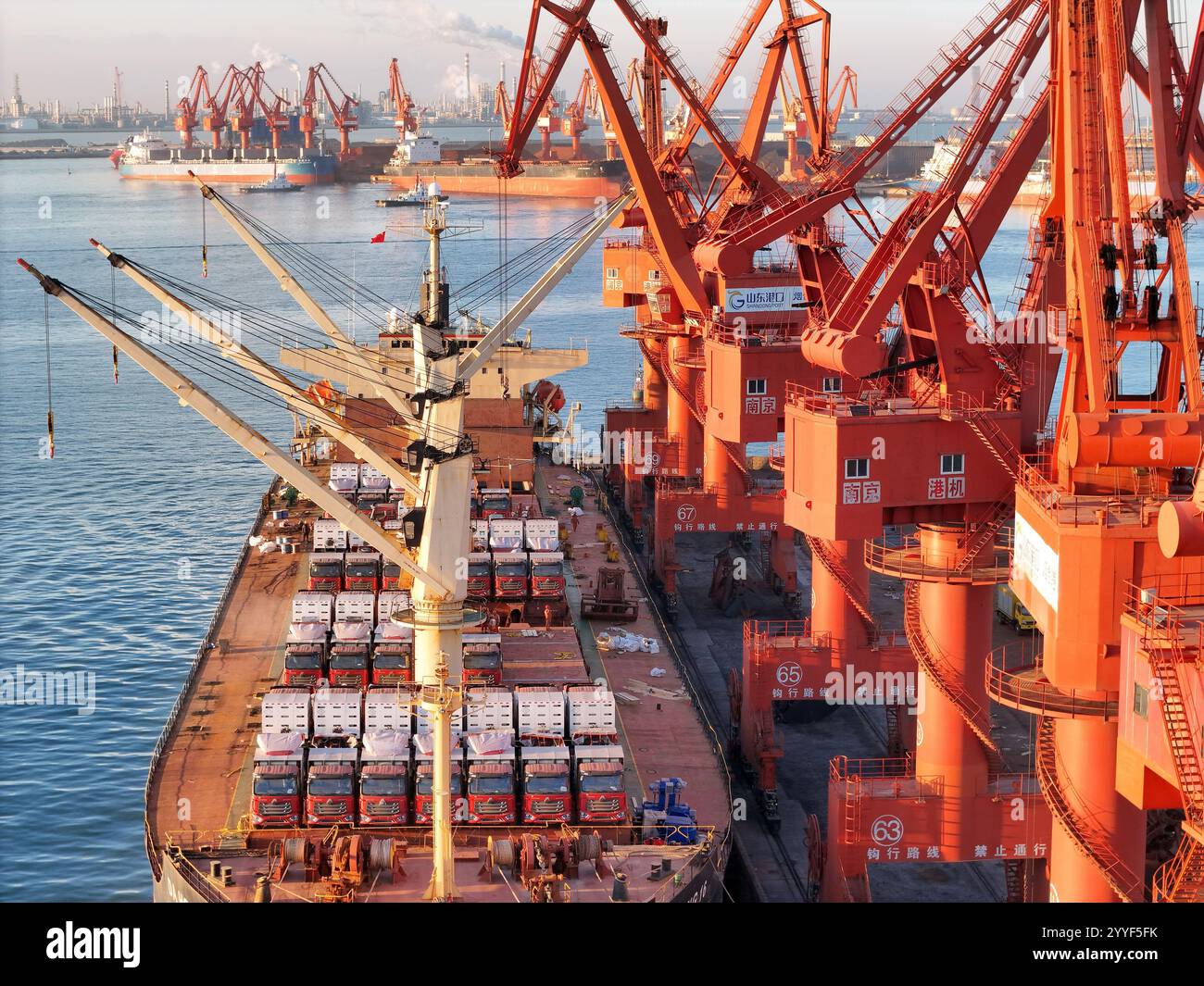 YANTAI, CHINA- DECEMBER 22, 2024 - A crane loads construction vehicles ...
