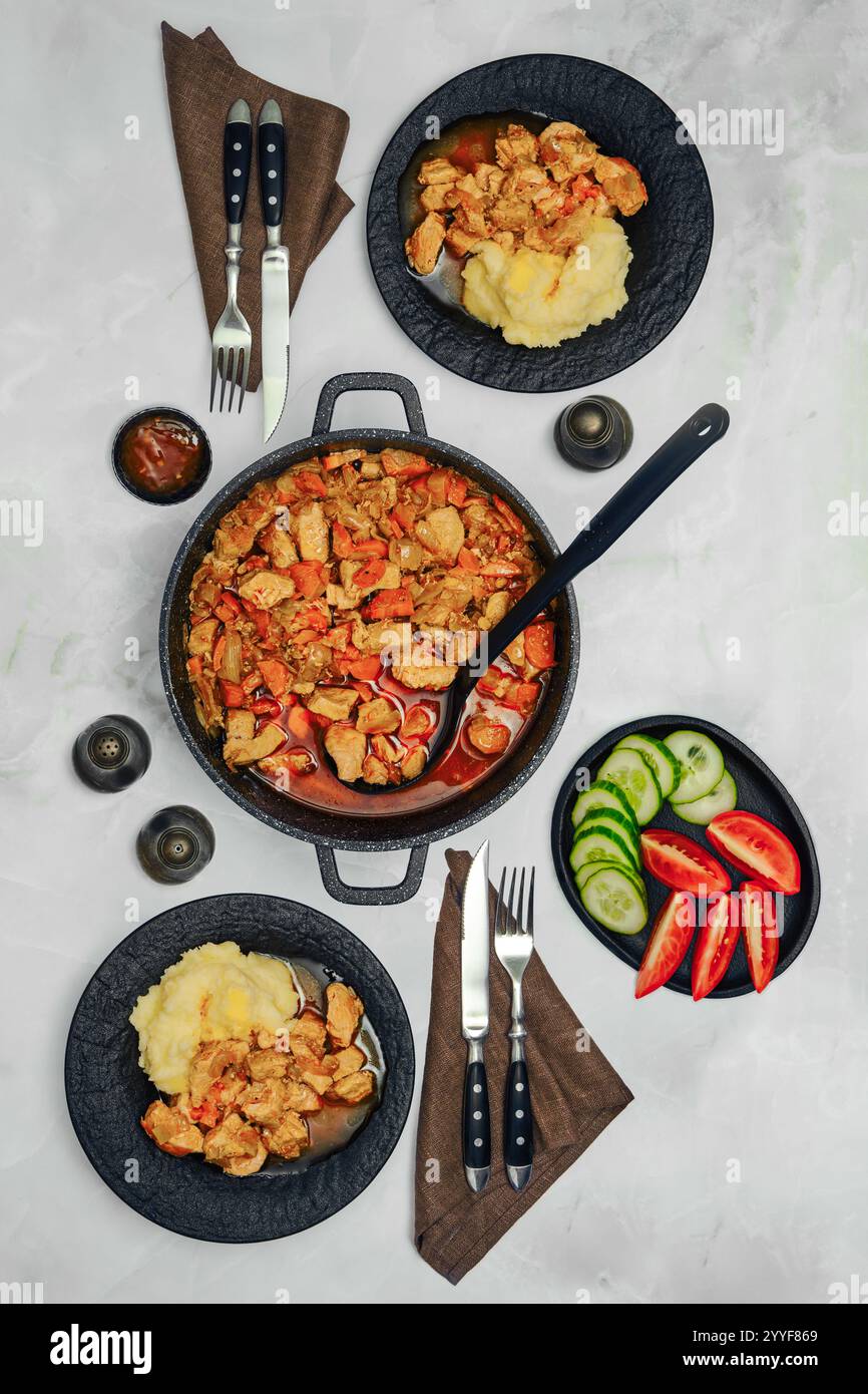 A hearty chicken or pork stew in a black plates, accompanied by creamy ...