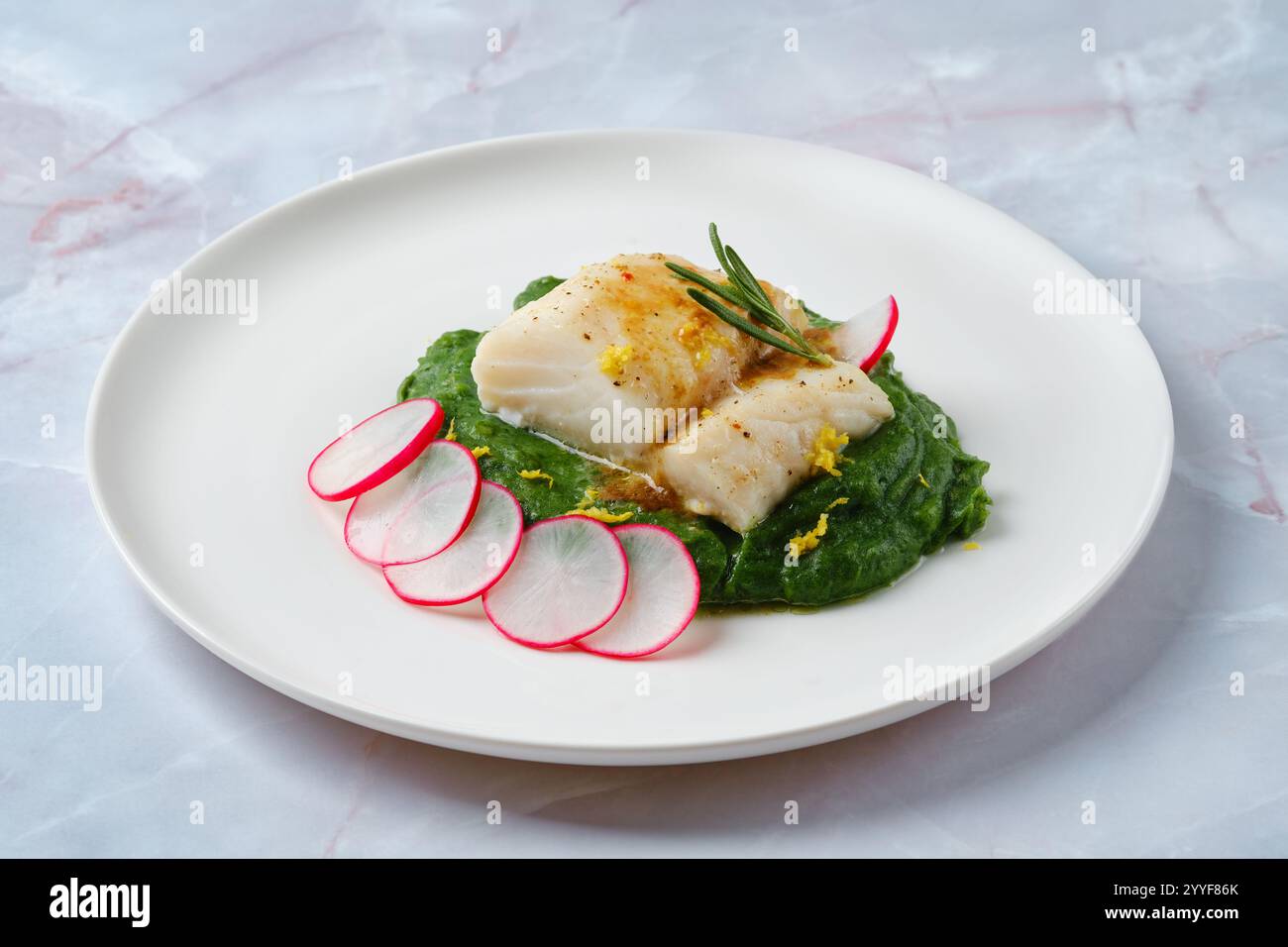 A beautiful presentation of a fish fillet garnished with herbs lies ...