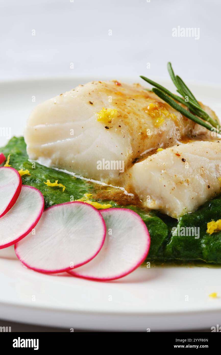 A tender white fish fillet is elegantly placed atop vibrant wilted ...