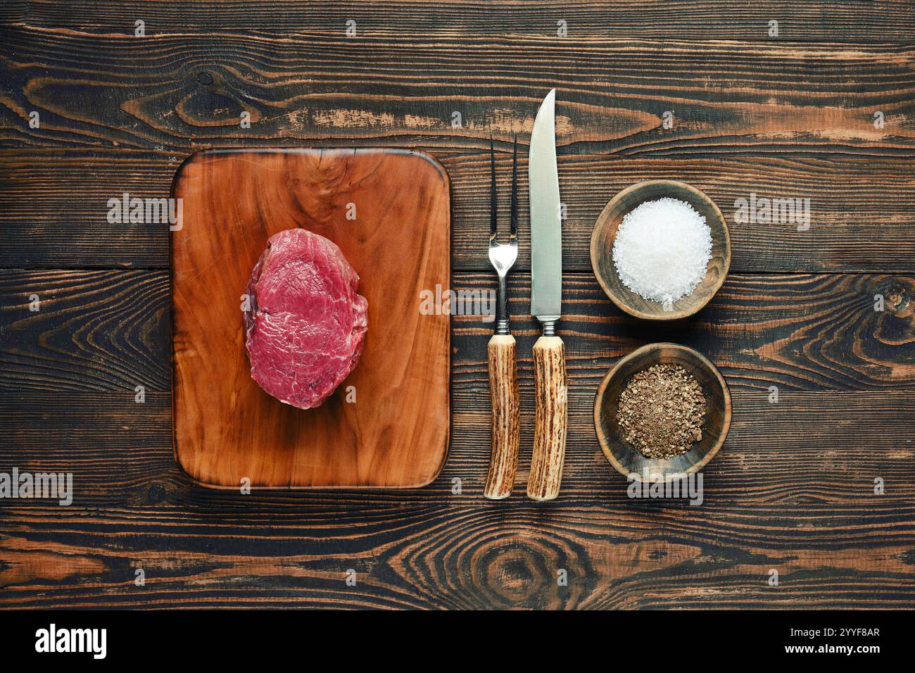A fresh prime cut of beef steak on a chopping board, next to bowls of ...