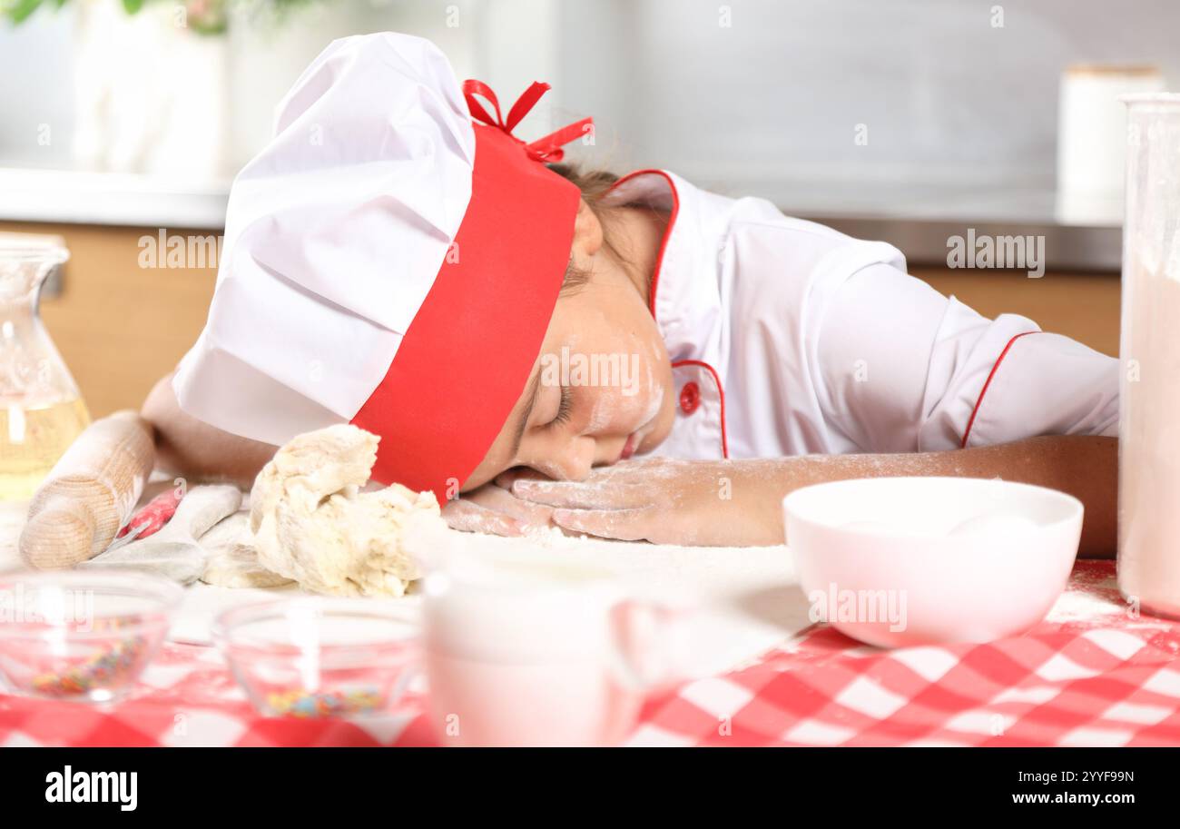 The little girl in the chef costume was tired and fell asleep at the ...