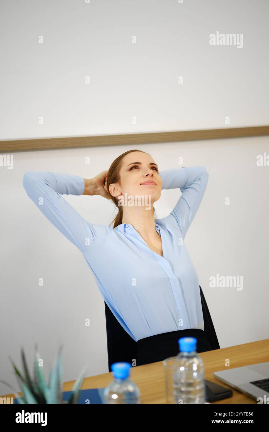 A woman sits comfortably at her desk in a contemporary office ...