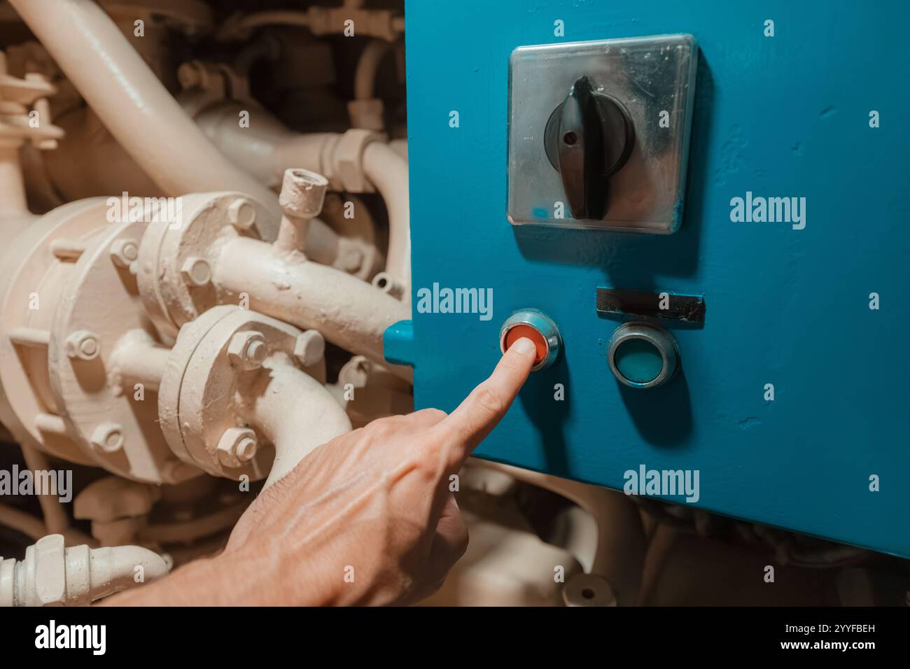 Hand activating emergency stop button on heavy machinery control panel ...