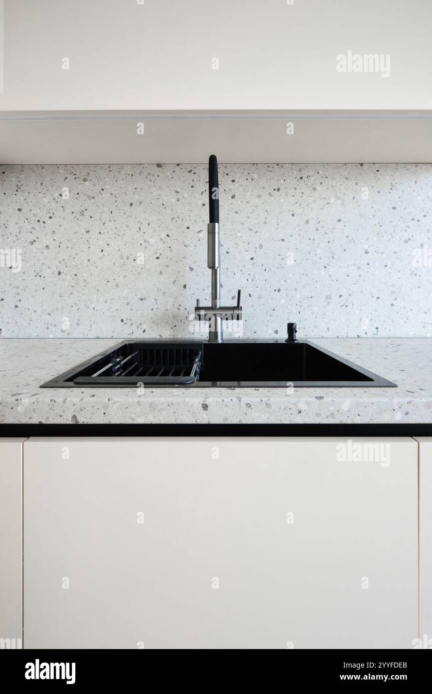 A sleek kitchen sink with a matte black faucet and a speckled white ...