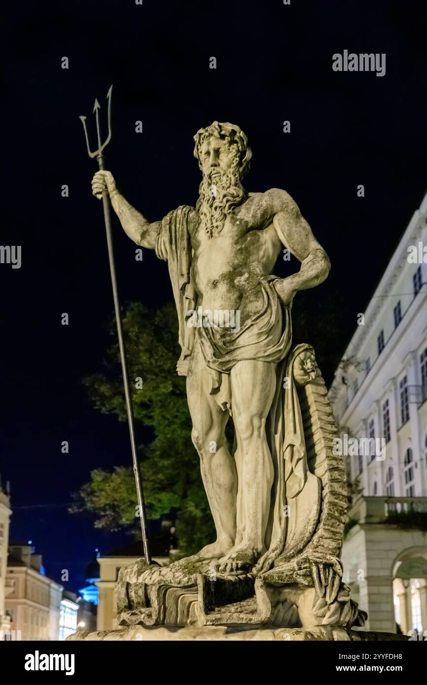 A statue of a man holding a trident is standing in front of a building ...