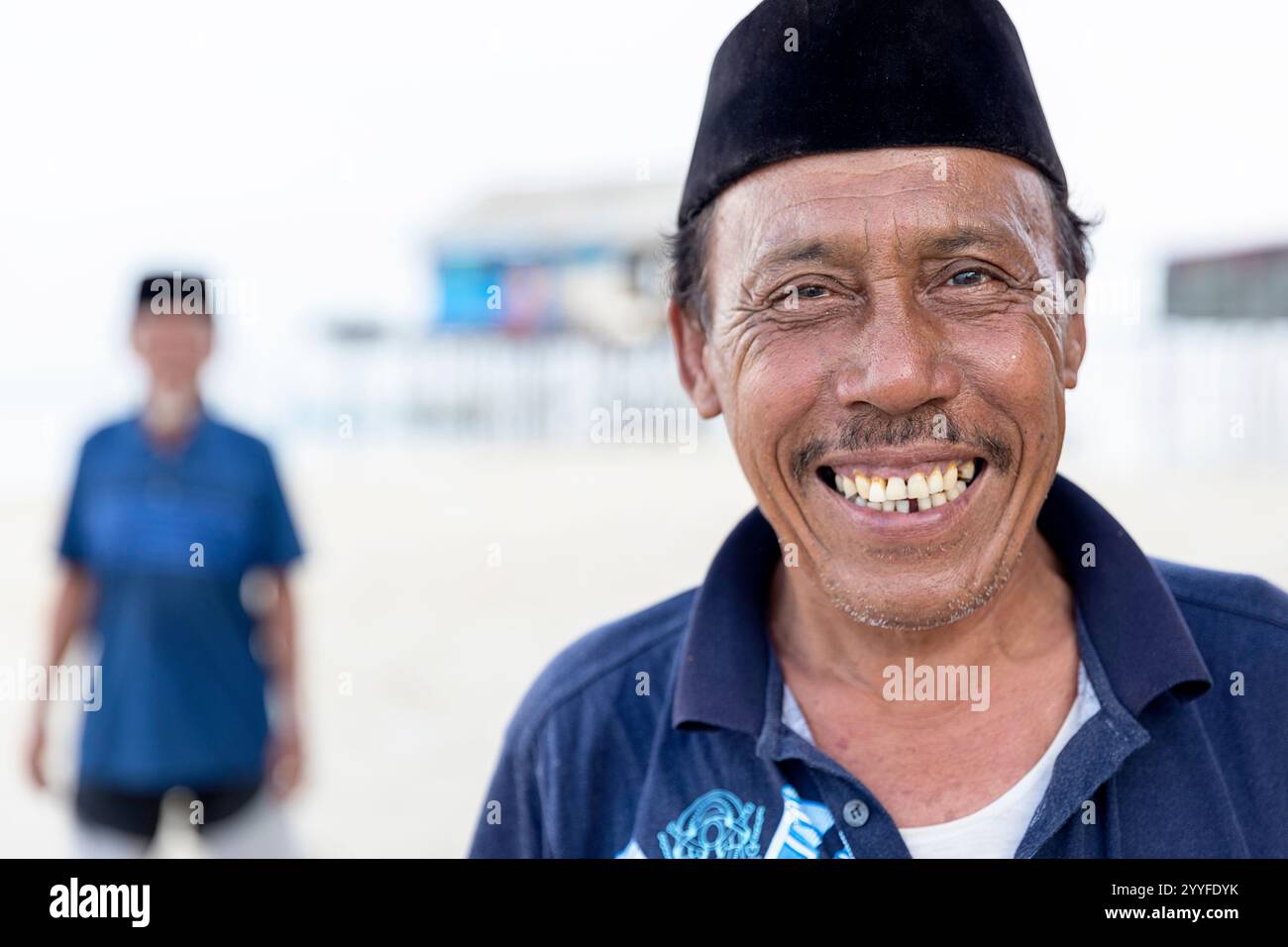 Portrait of a smiling bajau man with traditional hat in a small village ...