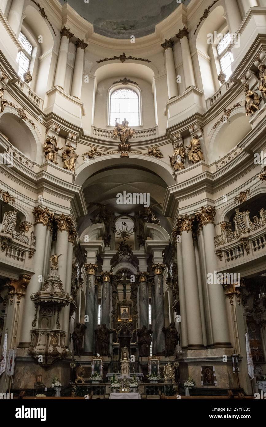 The inside of a church with a very high ceiling and a lot of gold decorations. The light is ...
