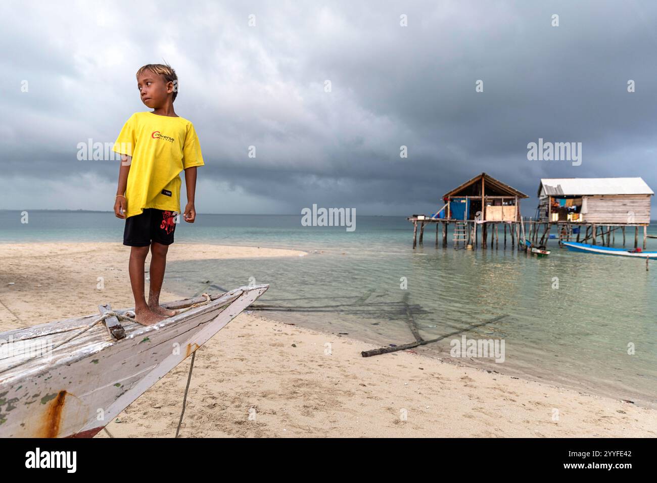 Bajau kid standing on old wooden boat in a small traditional bajau ...