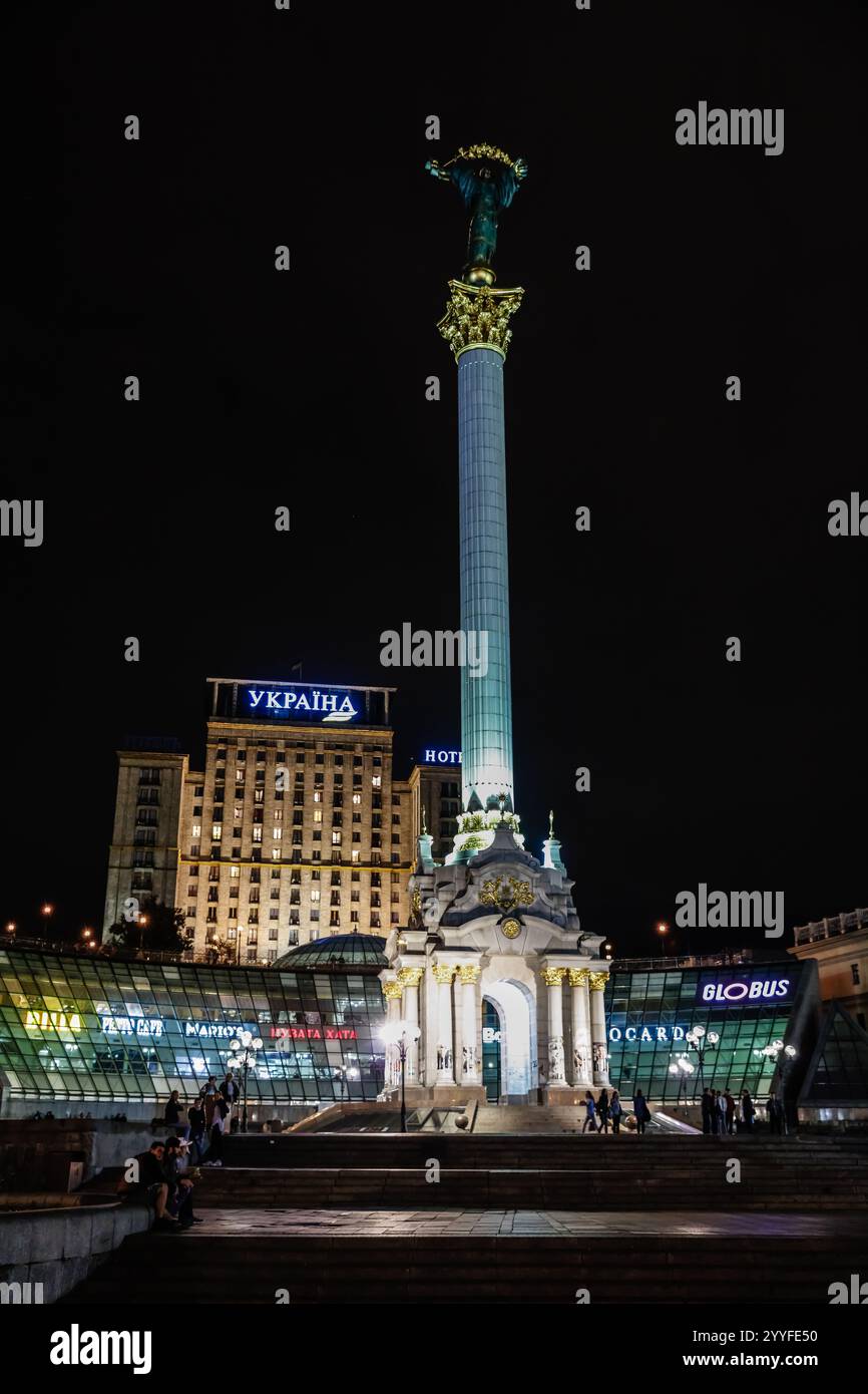A tall building with a statue of a woman on top. The building is lit up ...
