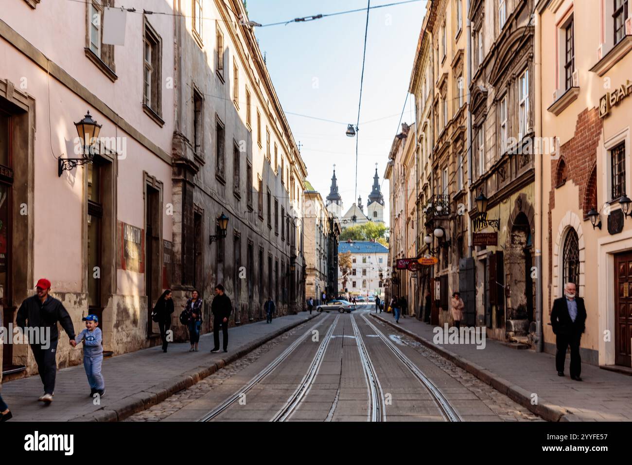 A busy city street with people walking and cars driving. The street is ...