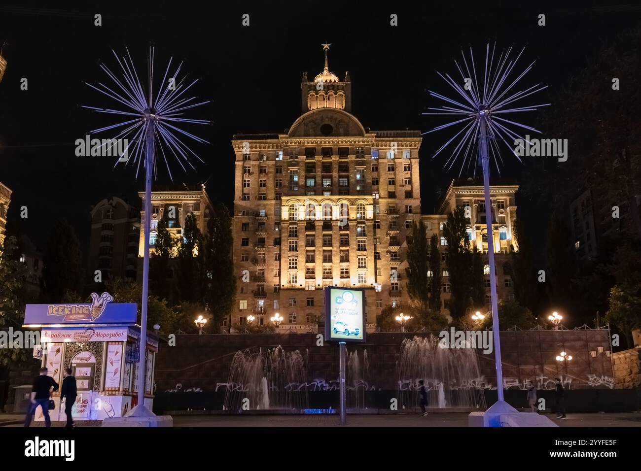A large building with two tall lights on top of it. The lights are blue ...