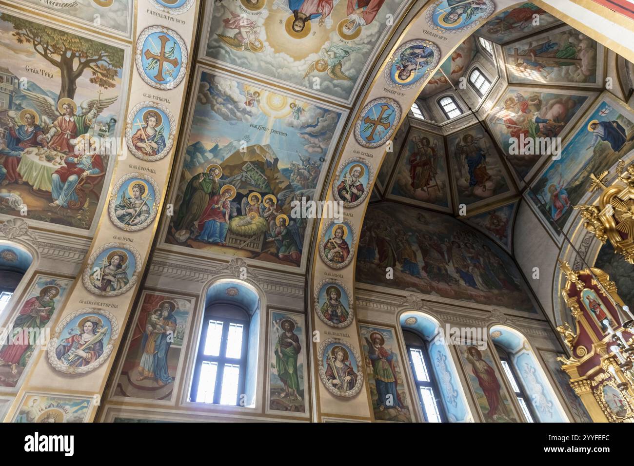The ceiling of a church is decorated with many paintings of religious ...