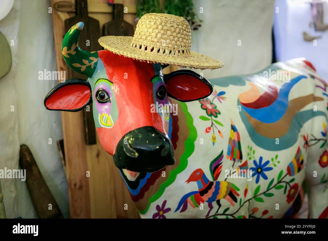 A cow with a straw hat on its head. The cow is painted in bright colors ...