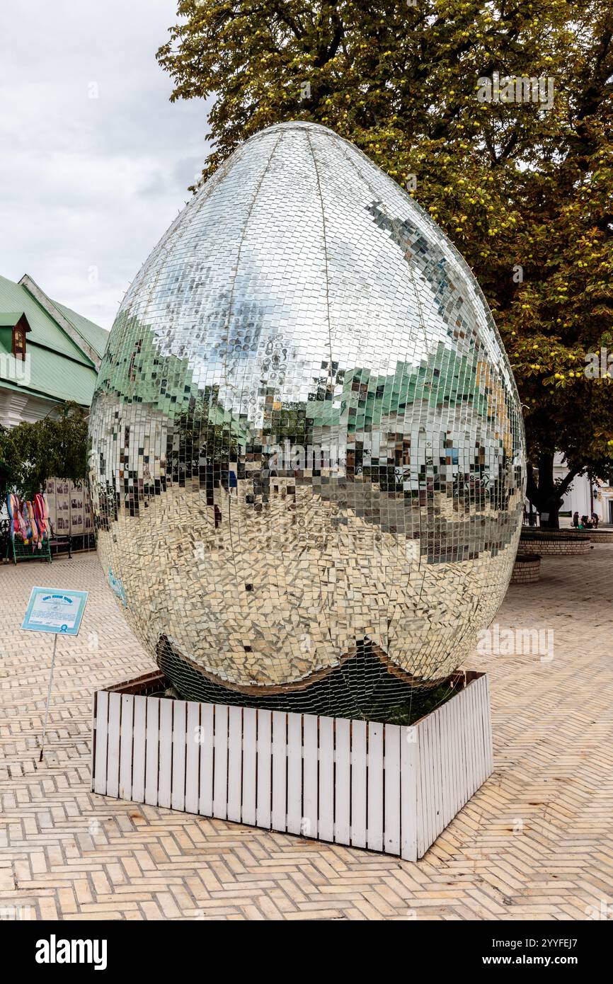 A large egg shaped sculpture is on display in a courtyard. The egg is ...