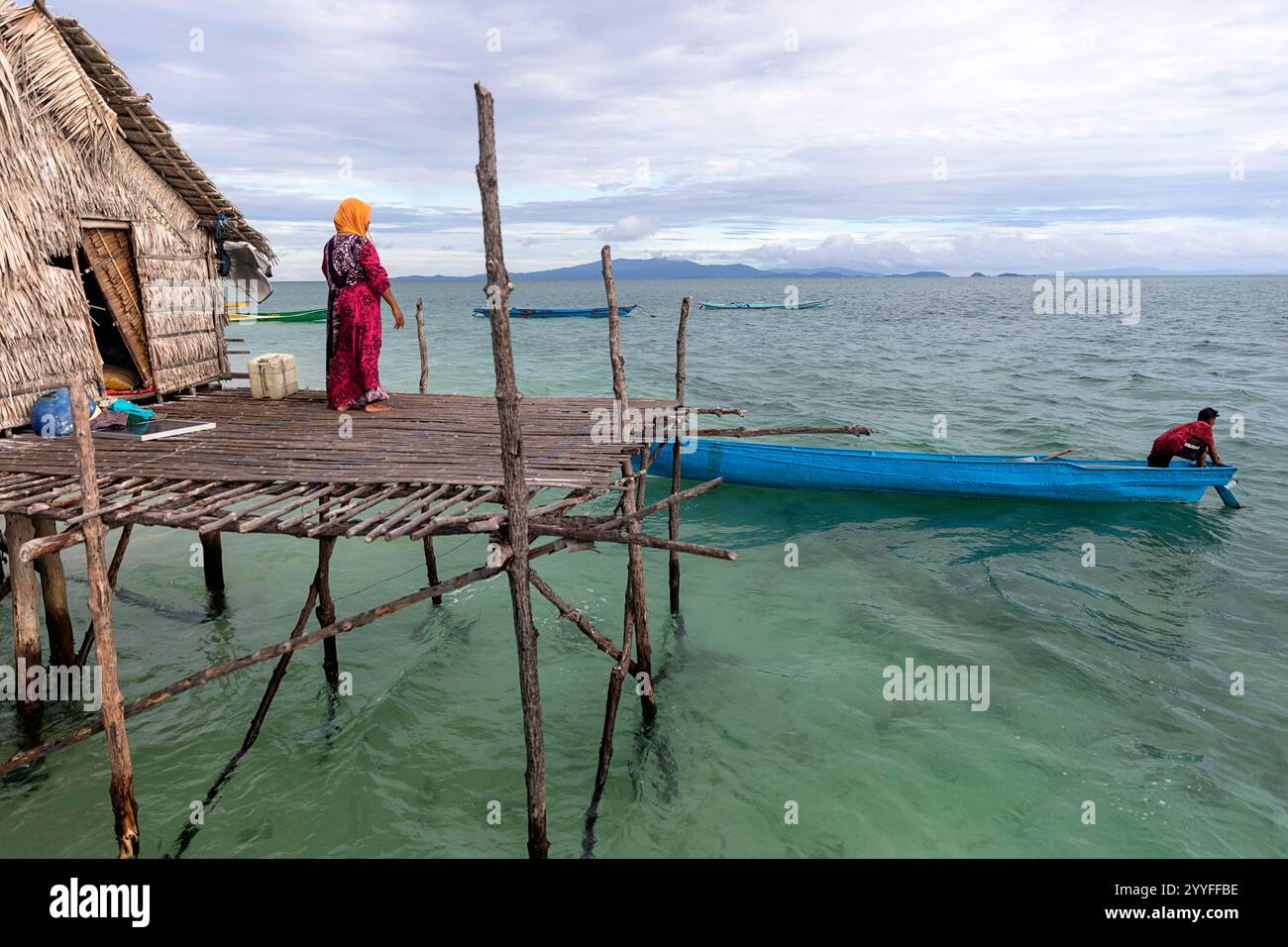 Woman in traditional clothes from bajau tribe on a porch of a wooden ...