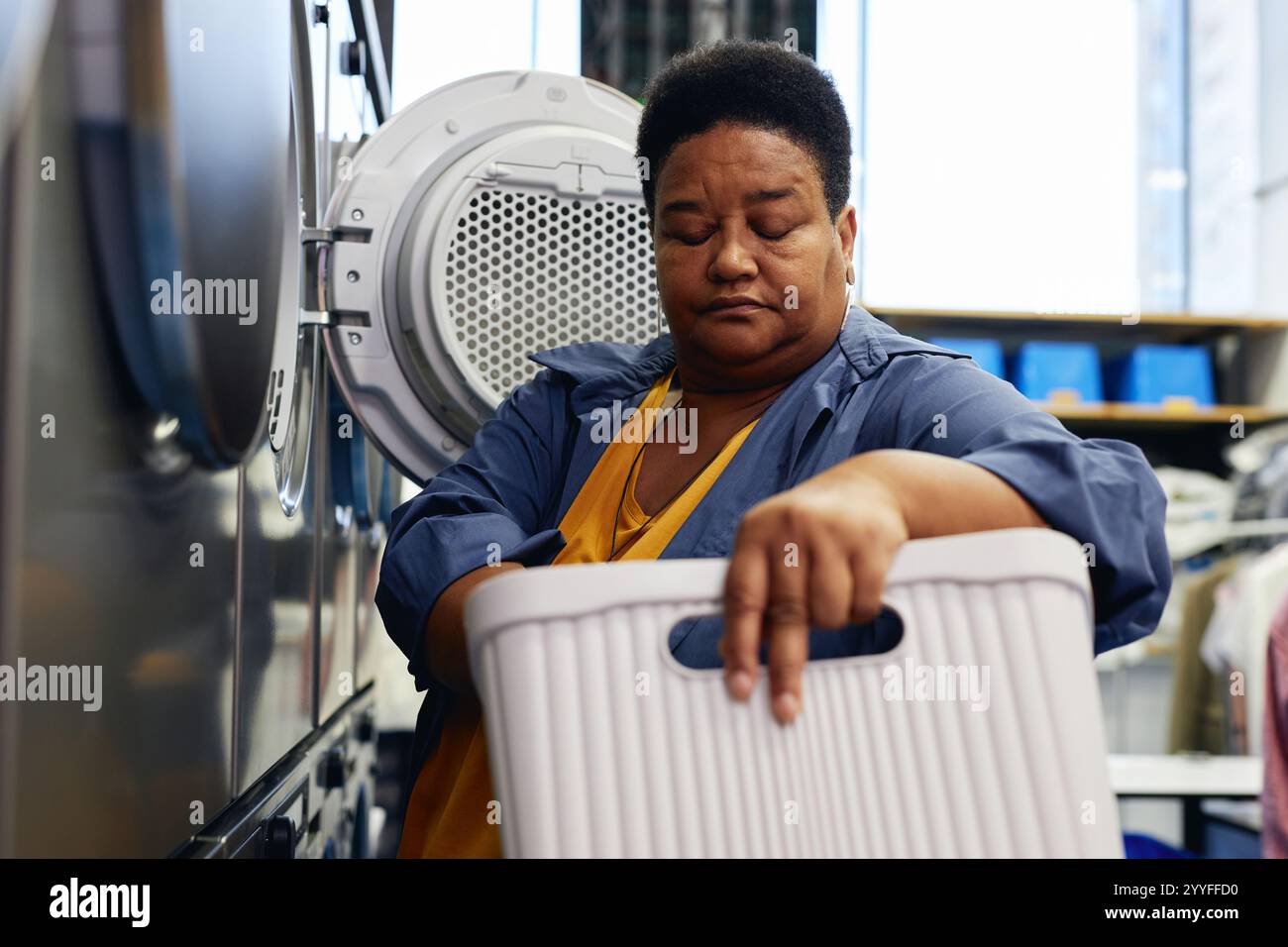 Medium portrait shot of senior Black woman loading clothes from basket ...